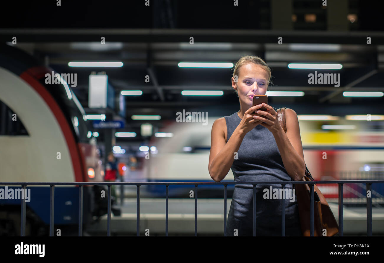 Pretty, young female commuter waiting for her daily train in a modern ...