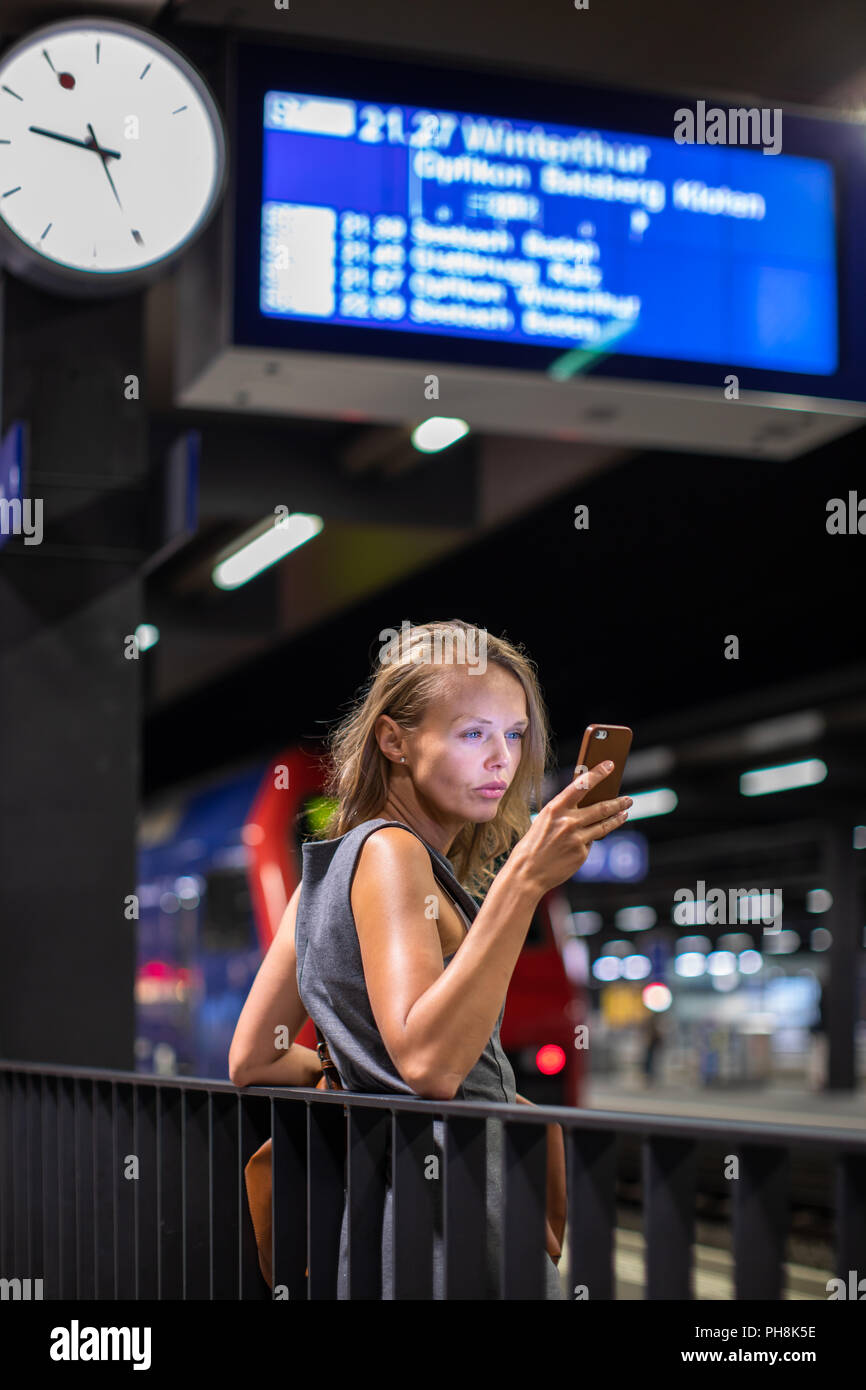 Pretty, young female commuter waiting for her daily train in a modern ...