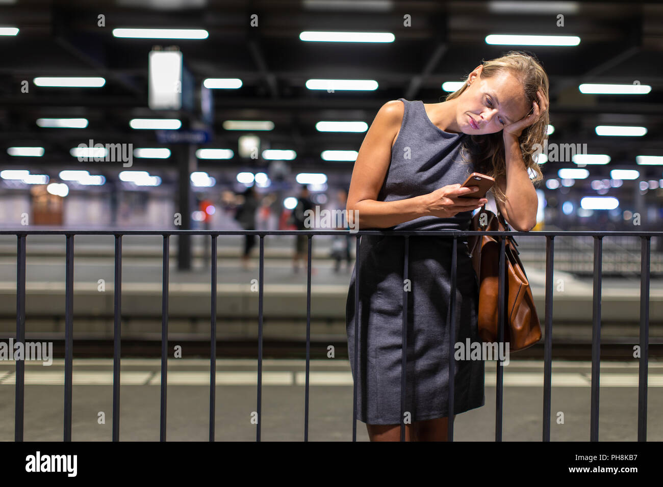 Pretty, young female commuter waiting for her daily train in a modern ...