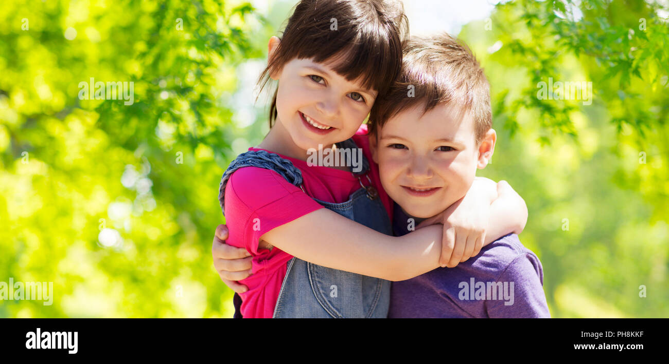 happy kids hugging over green natural background Stock Photo - Alamy