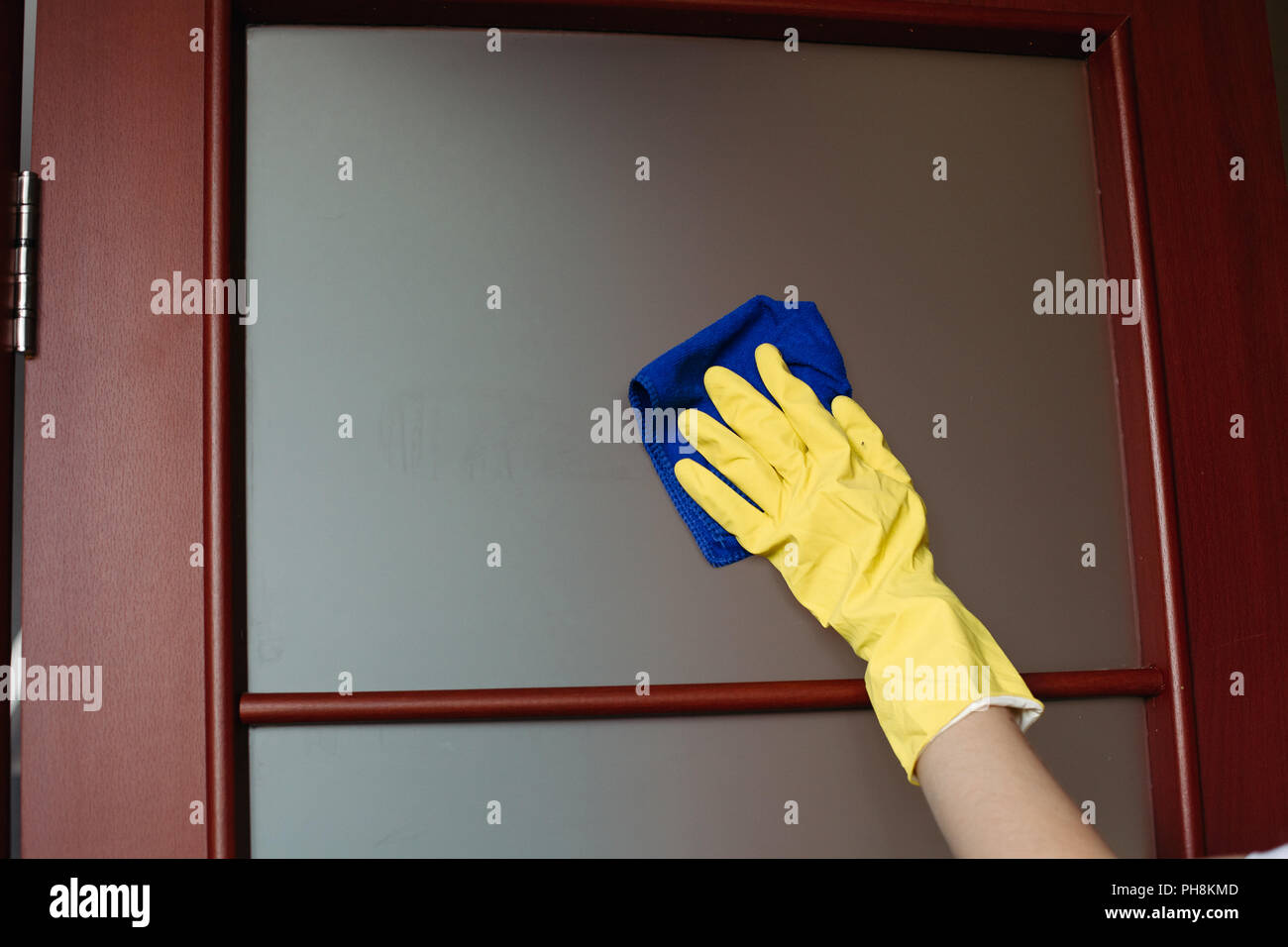 Crop of housewife hands wearing yellow gloves, cleaning dirty window ...