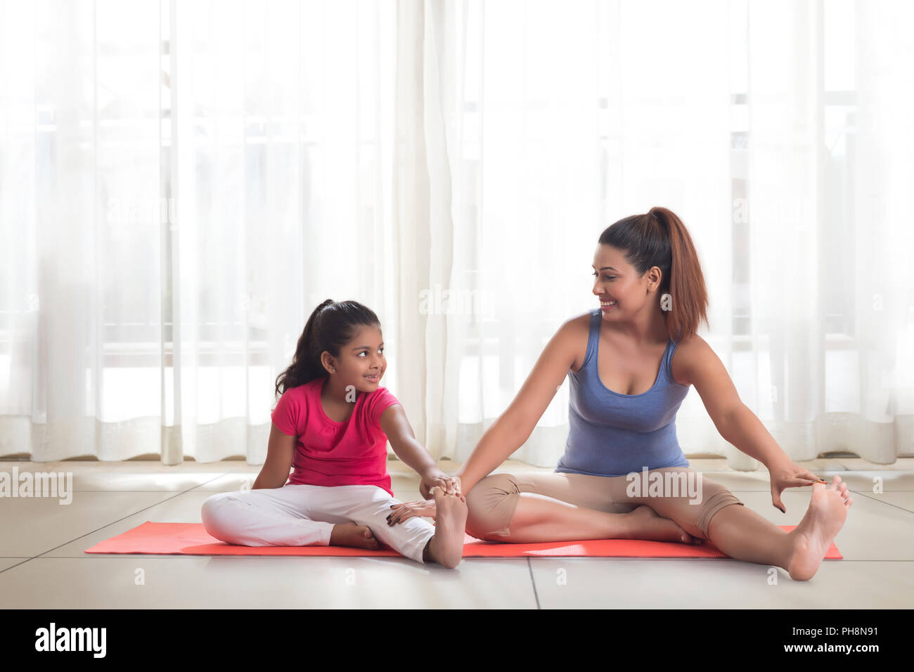 Mother teaching exercise to her daughter Stock Photo - Alamy