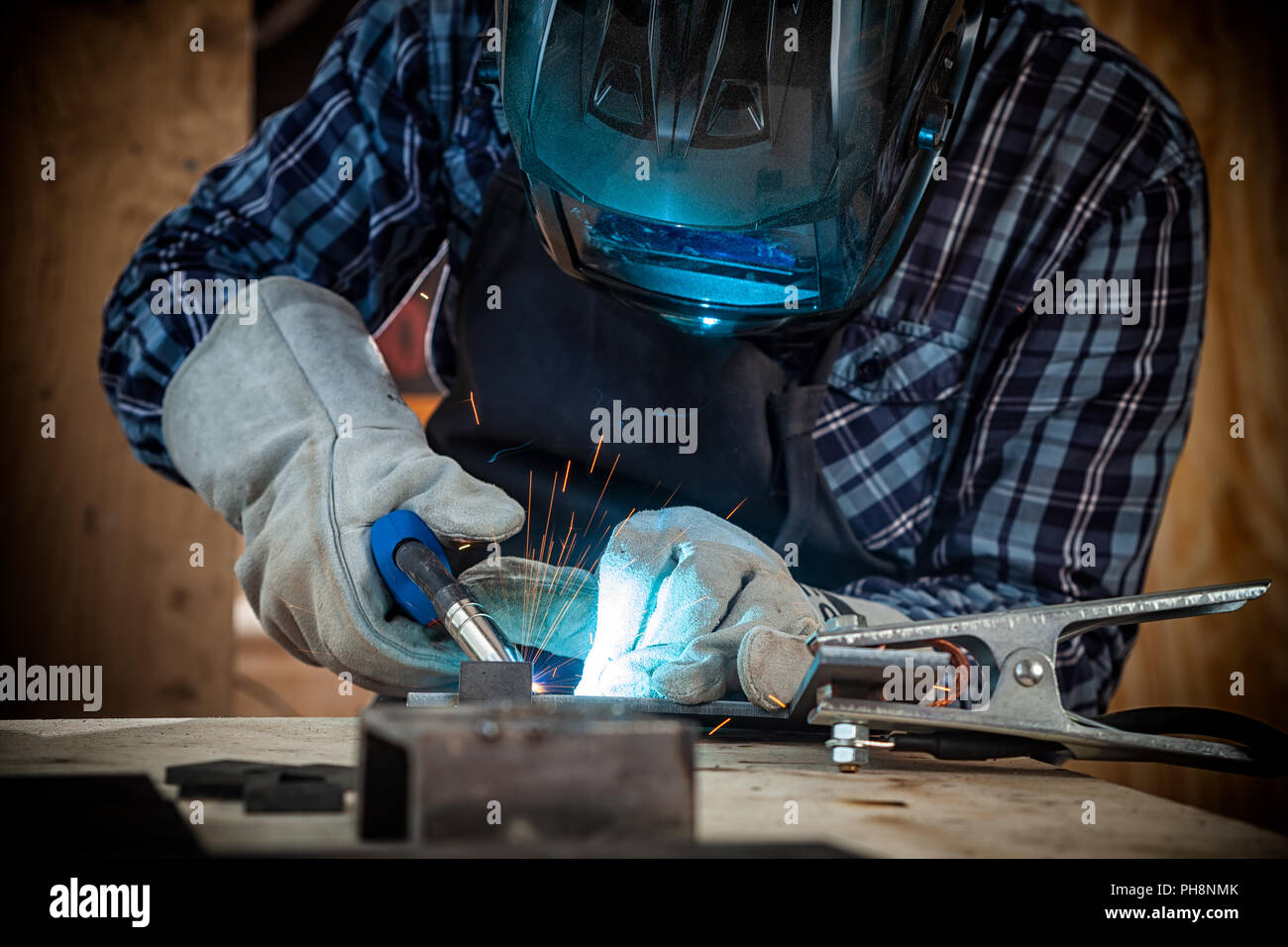 Close up of a young man welder in uniform, welding mask and welders ...