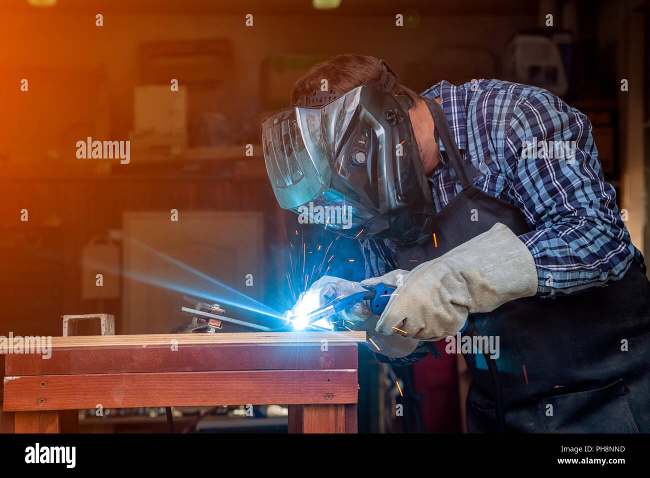 Strong man welder in work clothes hard working and welds with a welding ...