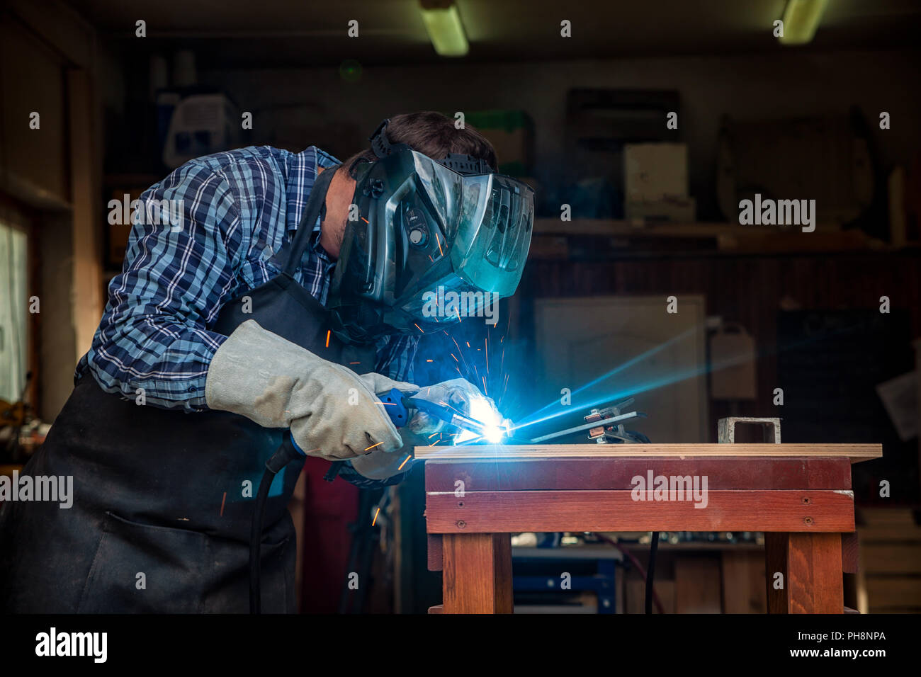 Strong man welder in work clothes hard working and welds with a welding ...