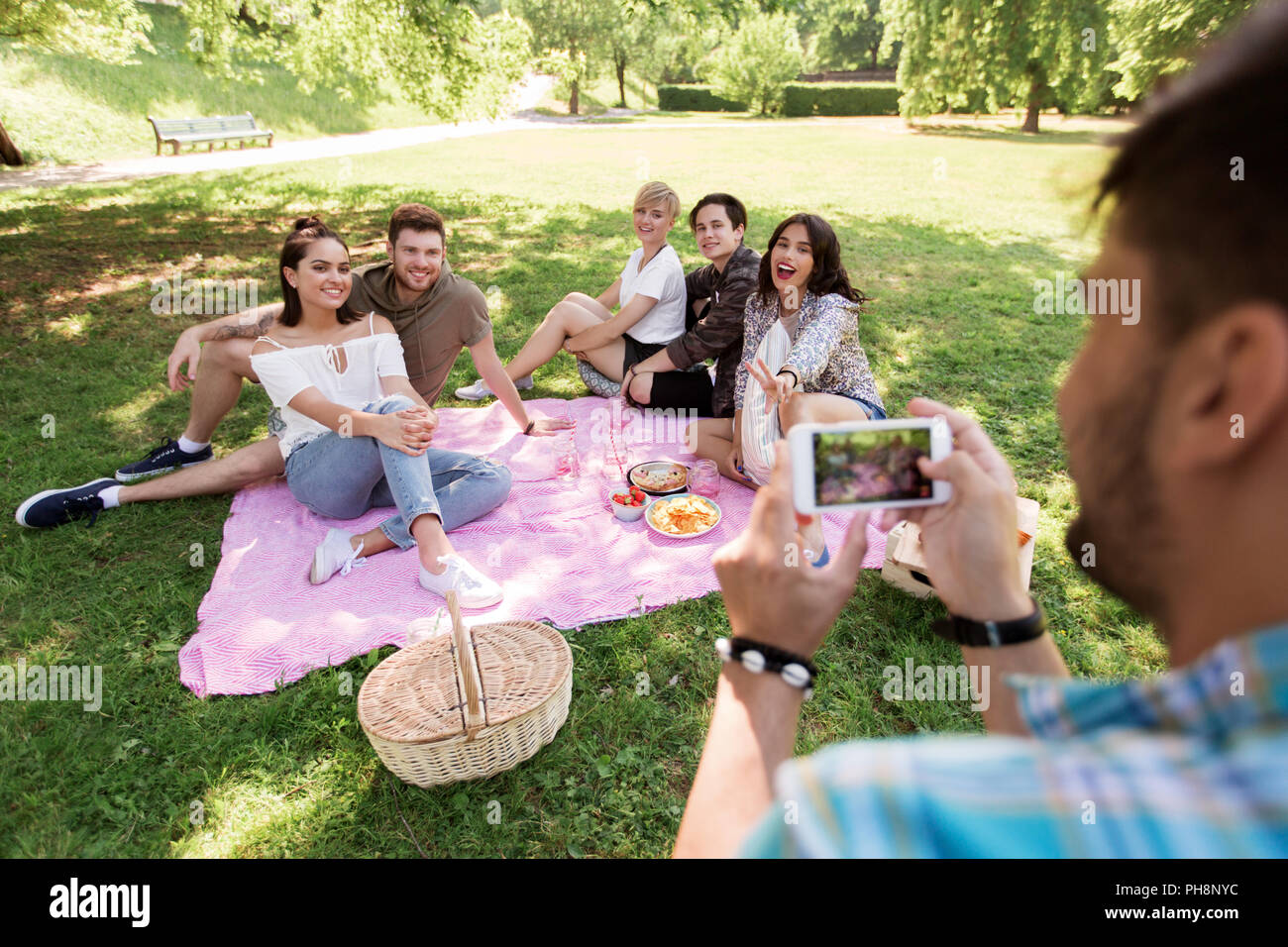 man photographing friends by smartphone at picnic Stock Photo - Alamy