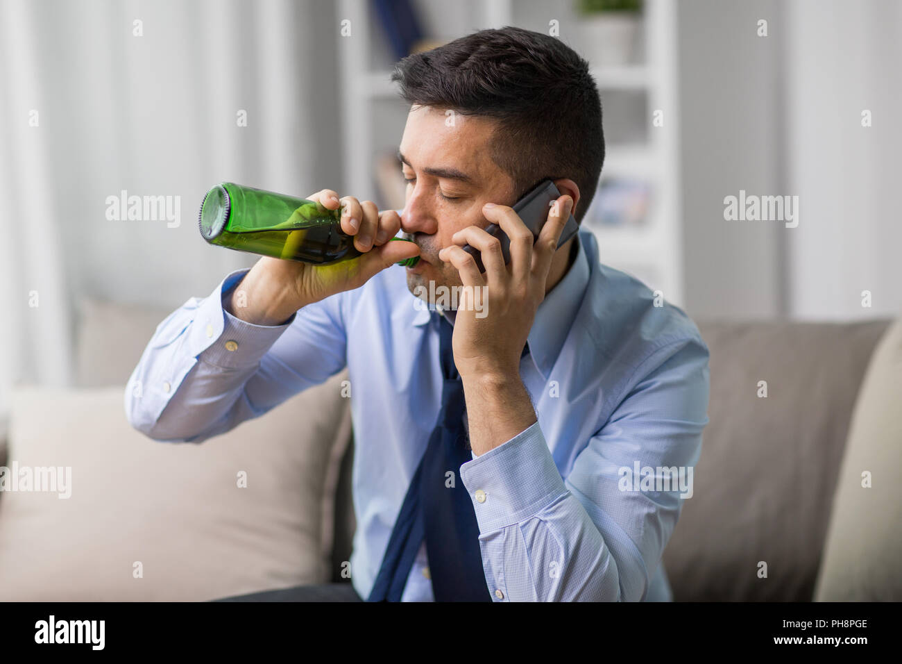 man drinking alcohol and calling on smartphone Stock Photo - Alamy