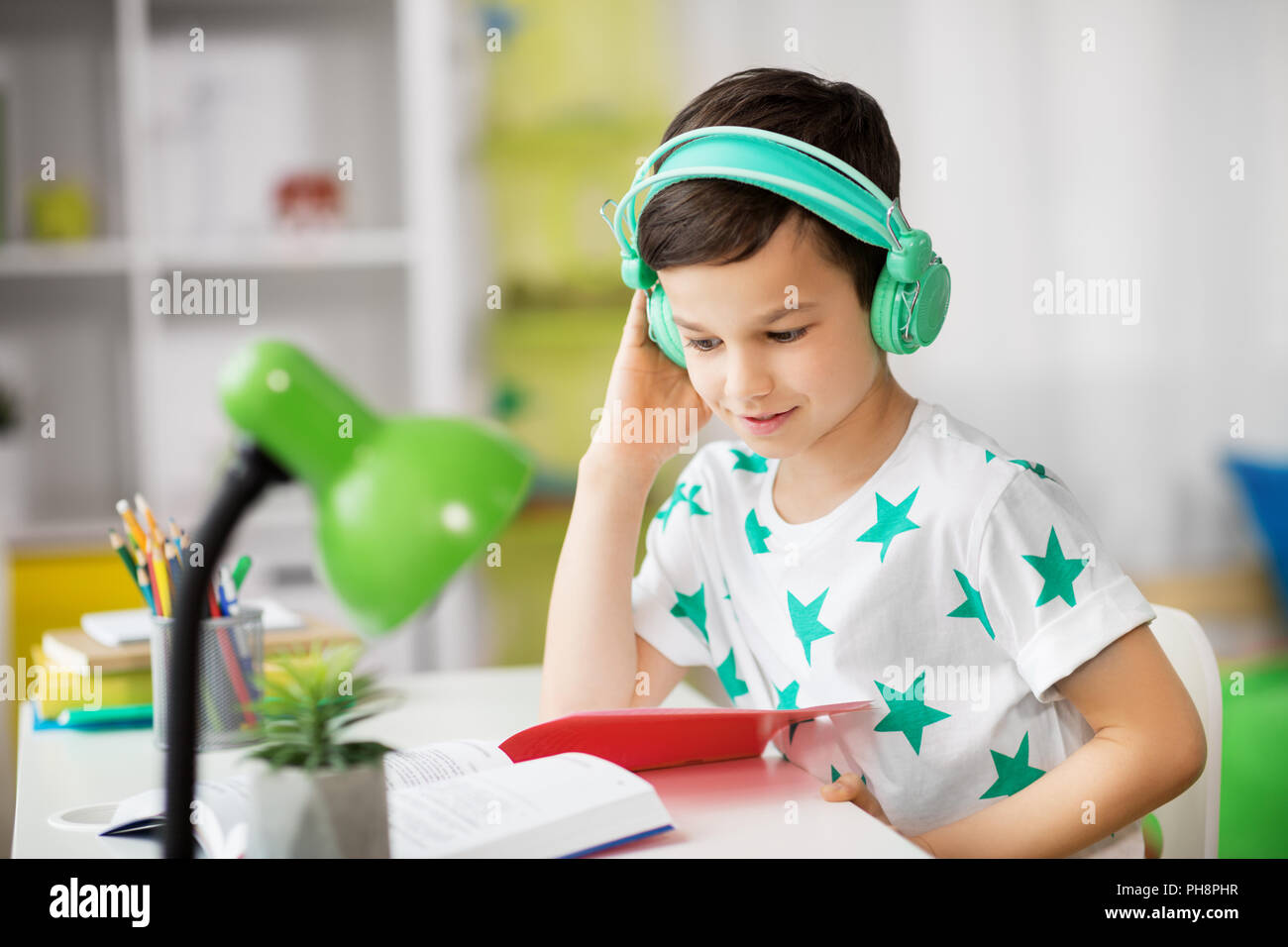 student boy in headphones reading book at home Stock Photo - Alamy