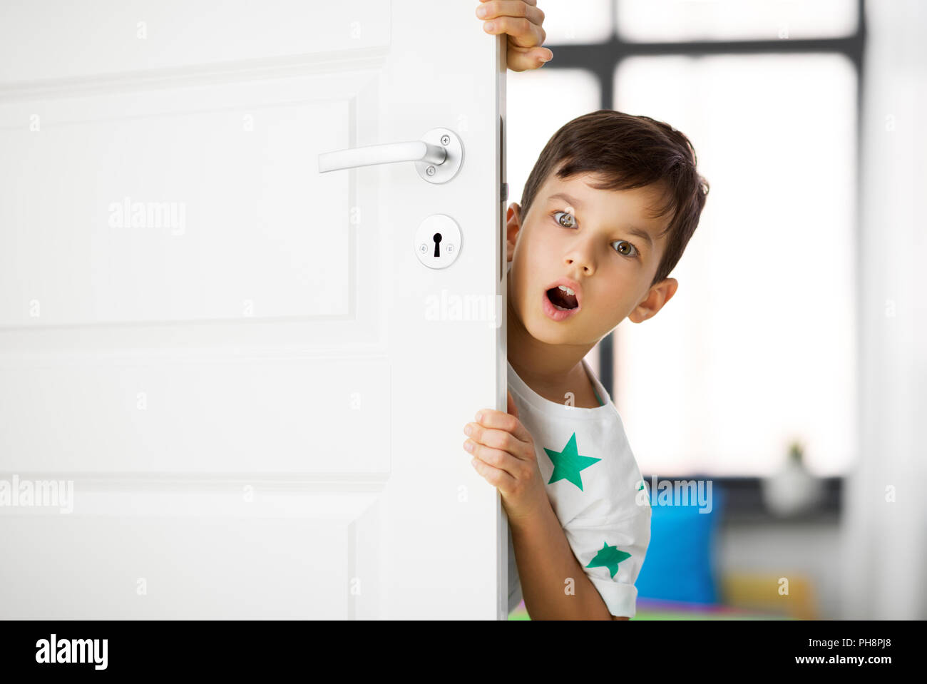 surprised little boy behind door at home Stock Photo - Alamy