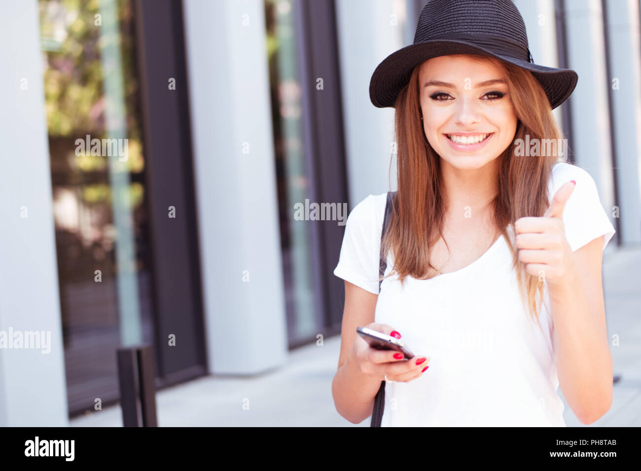 Attractive Girl with Phone Showing Thumbs Up Stock Photo - Alamy