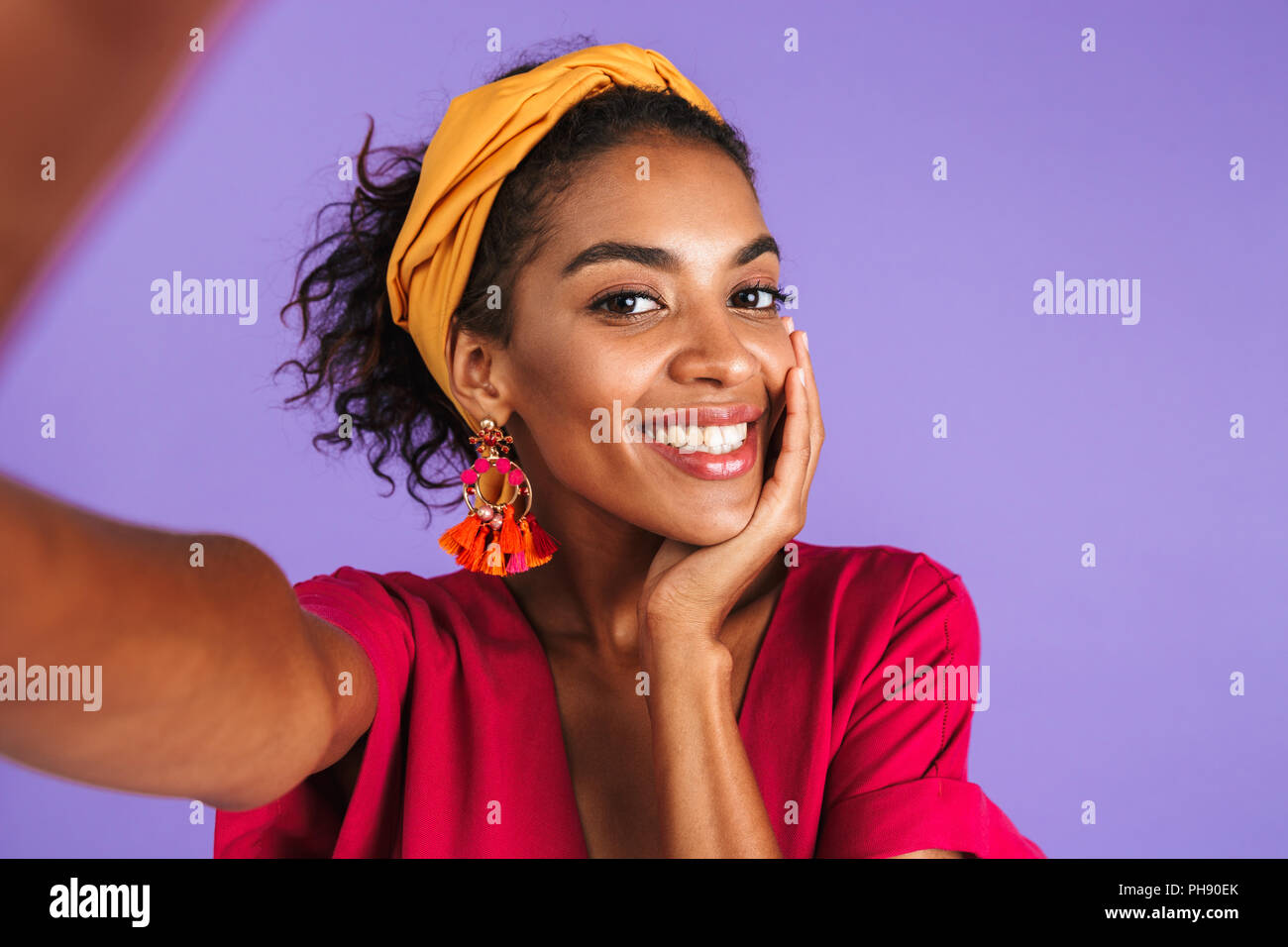 Smiling african woman in dress making selfie and looking at the camera ...