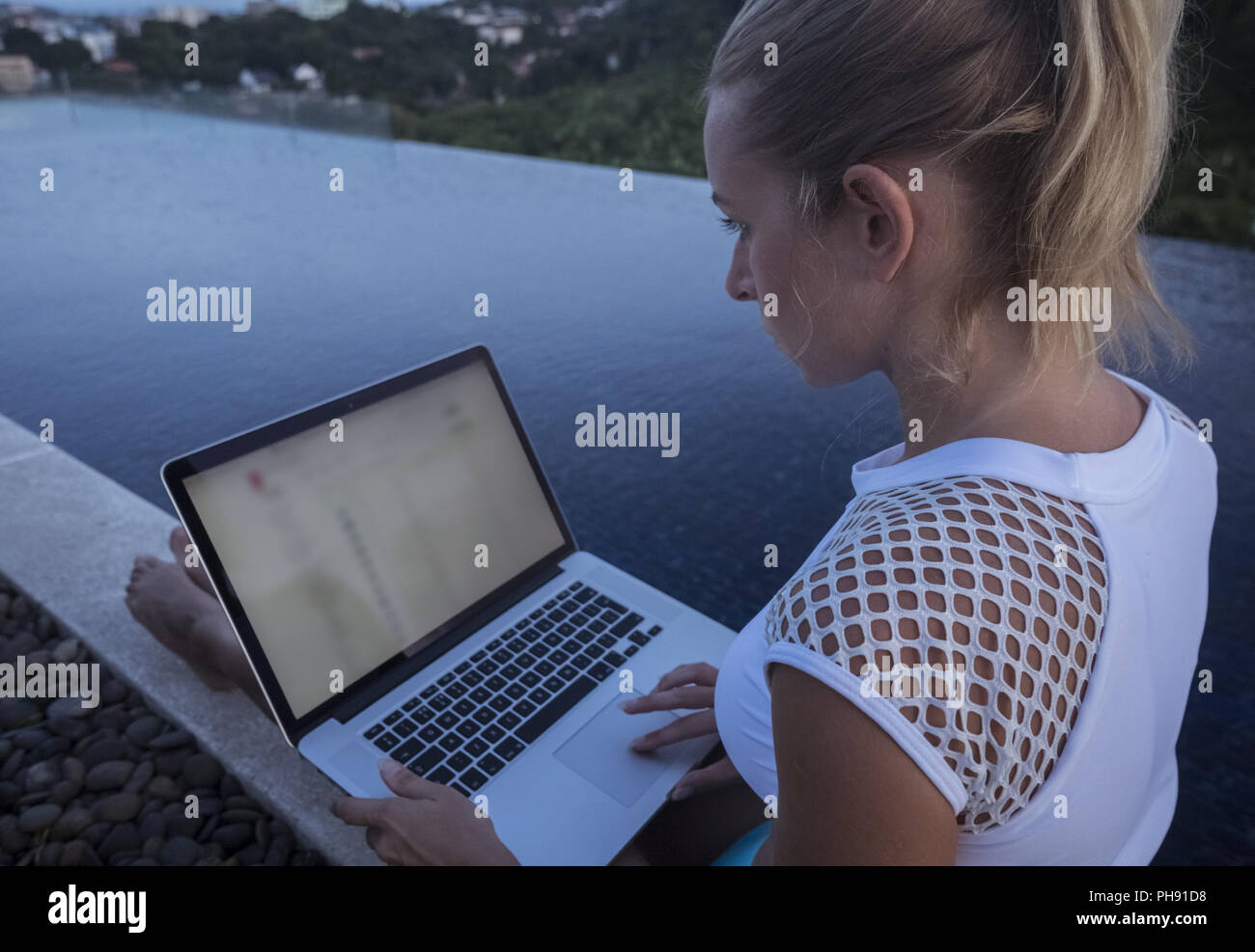 Pretty blonde woman with laptop computer on a rooftop Stock Photo - Alamy