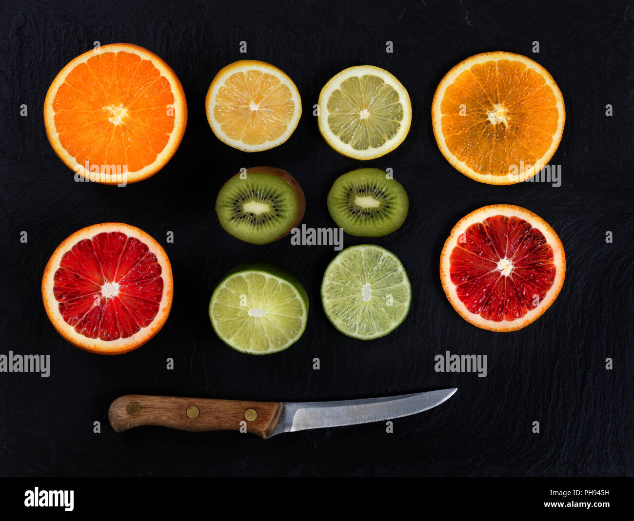 Sliced citrus fruit and knife on natural slate stone background Stock ...