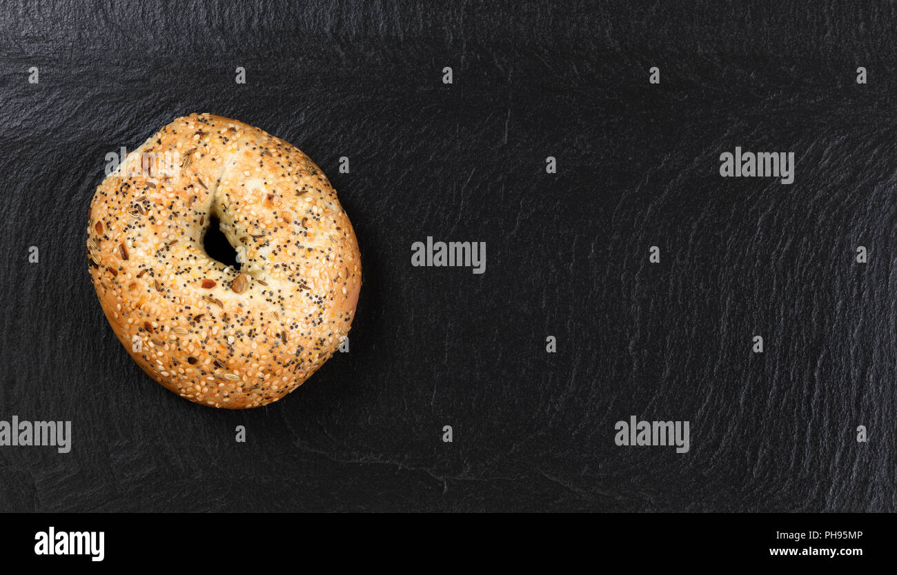 Large seeded bagel on natural slate stone background Stock Photo - Alamy