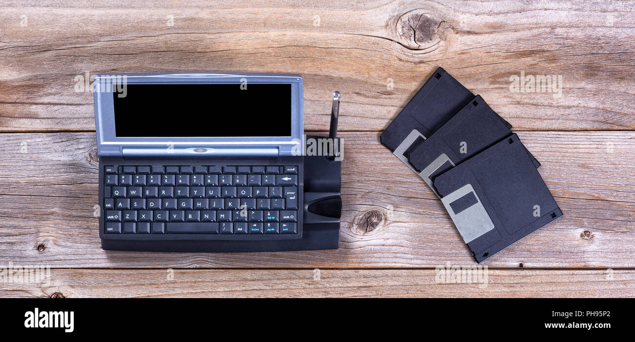 Vintage handheld computer and data disks on rustic wooden boards Stock ...
