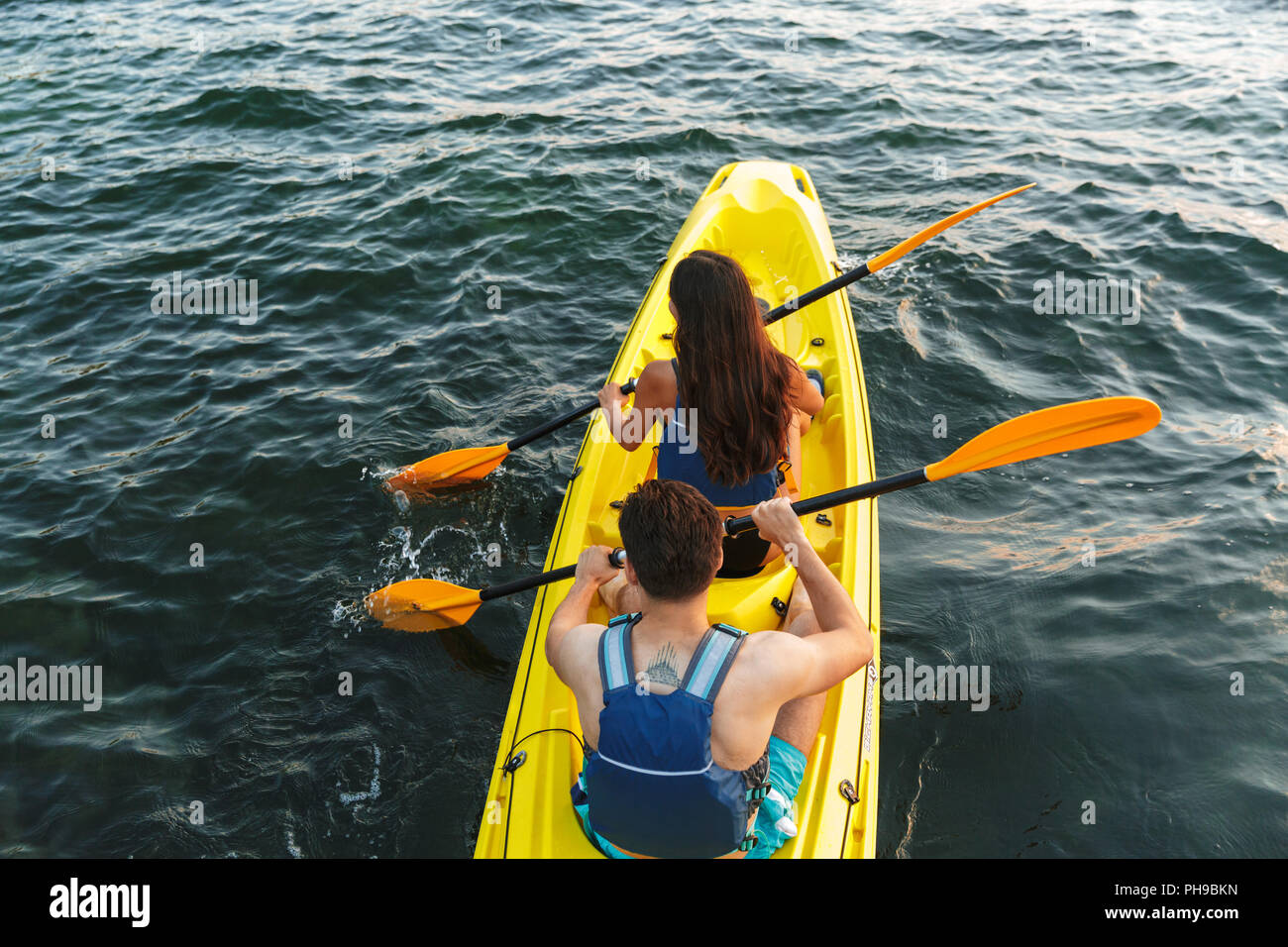 Rear view of beautiful young couple kayaking on lake together Stock ...