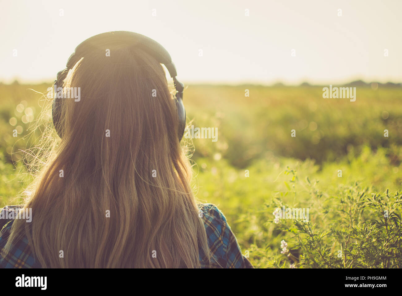 girl with headphones back view. looks into the distance with nature in ...