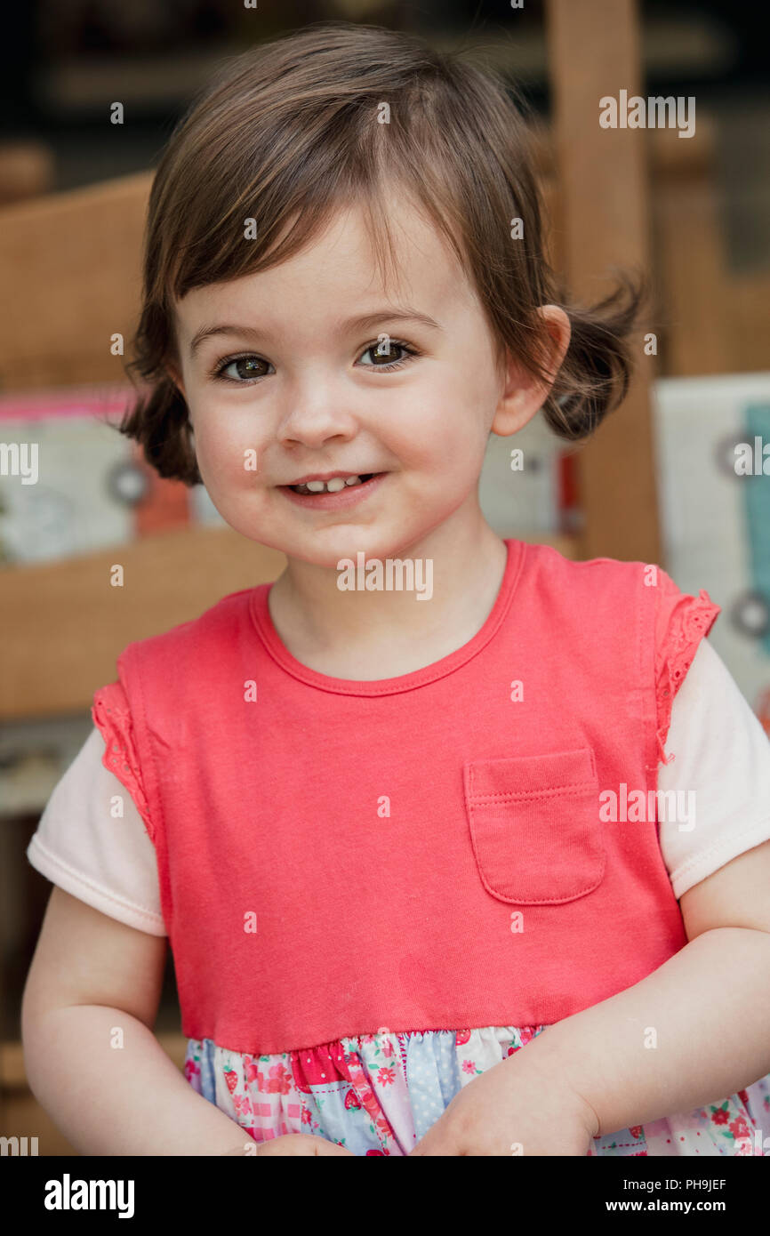 Front view of a little girl standing with curiosty in her face looking ...