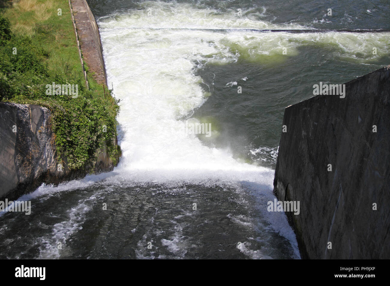 Dam wall and overflow of Iskar Dam. Water flowing over a dam wall. Mist ...