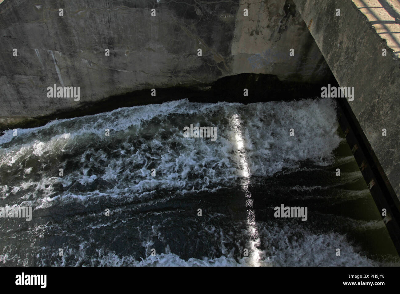Dam wall and overflow of Iskar Dam. Water flowing over a dam wall. Mist ...
