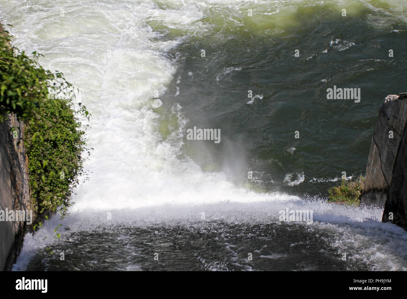 Dam wall and overflow of Iskar Dam. Water flowing over a dam wall. Mist ...