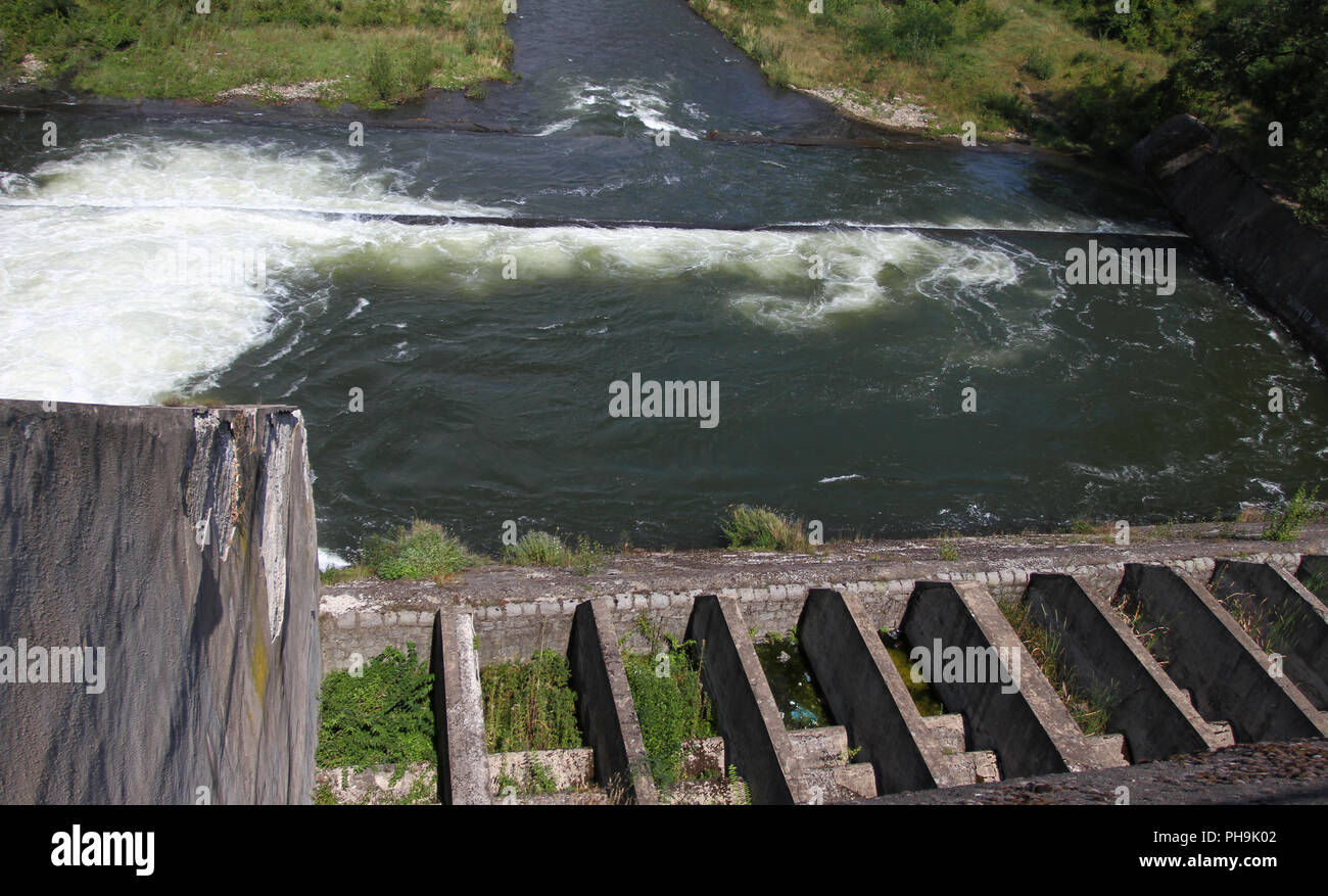 Dam wall and overflow of Iskar Dam. Water flowing over a dam wall. Mist ...