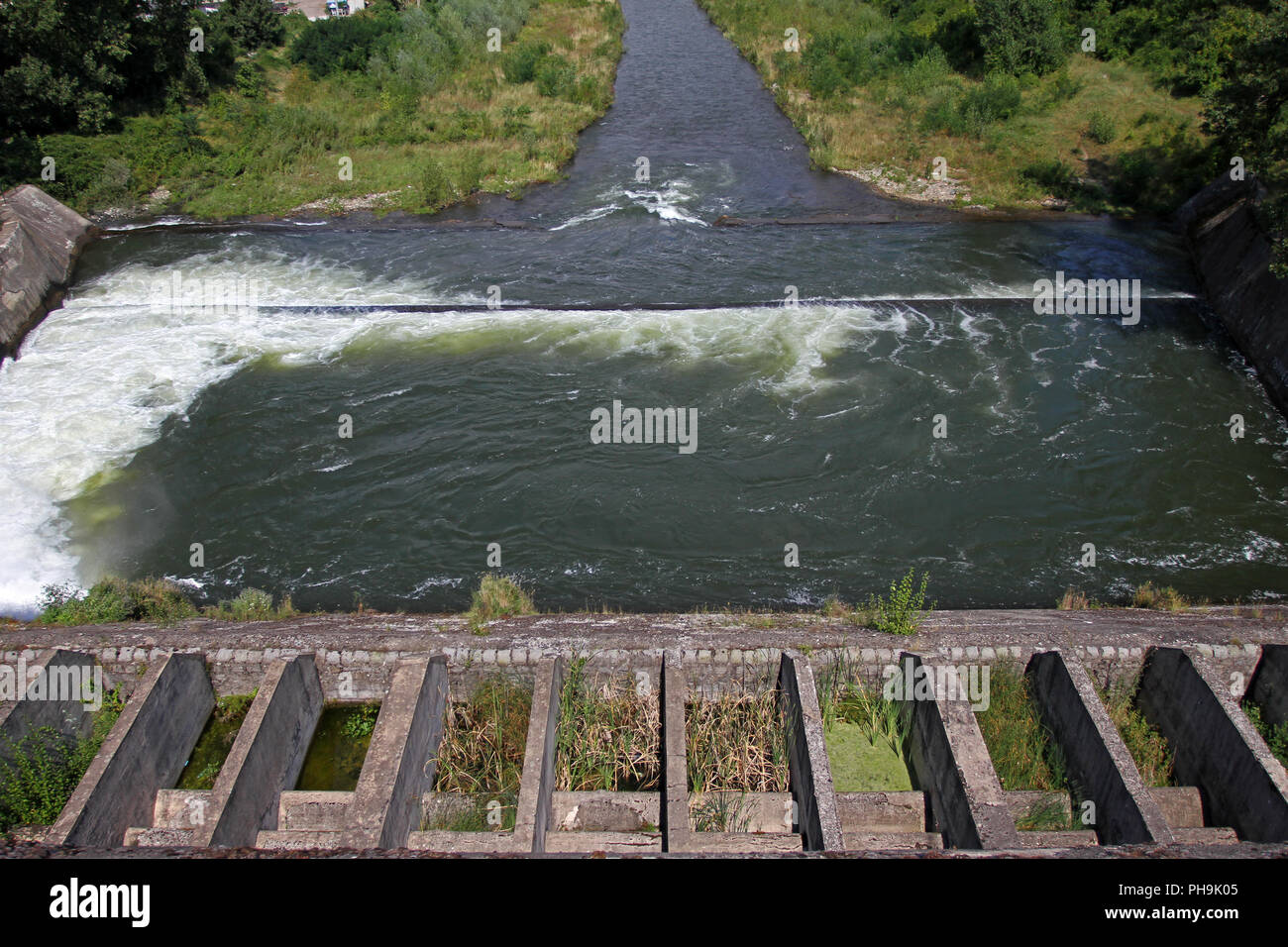 Dam wall and overflow of Iskar Dam. Water flowing over a dam wall. Mist ...