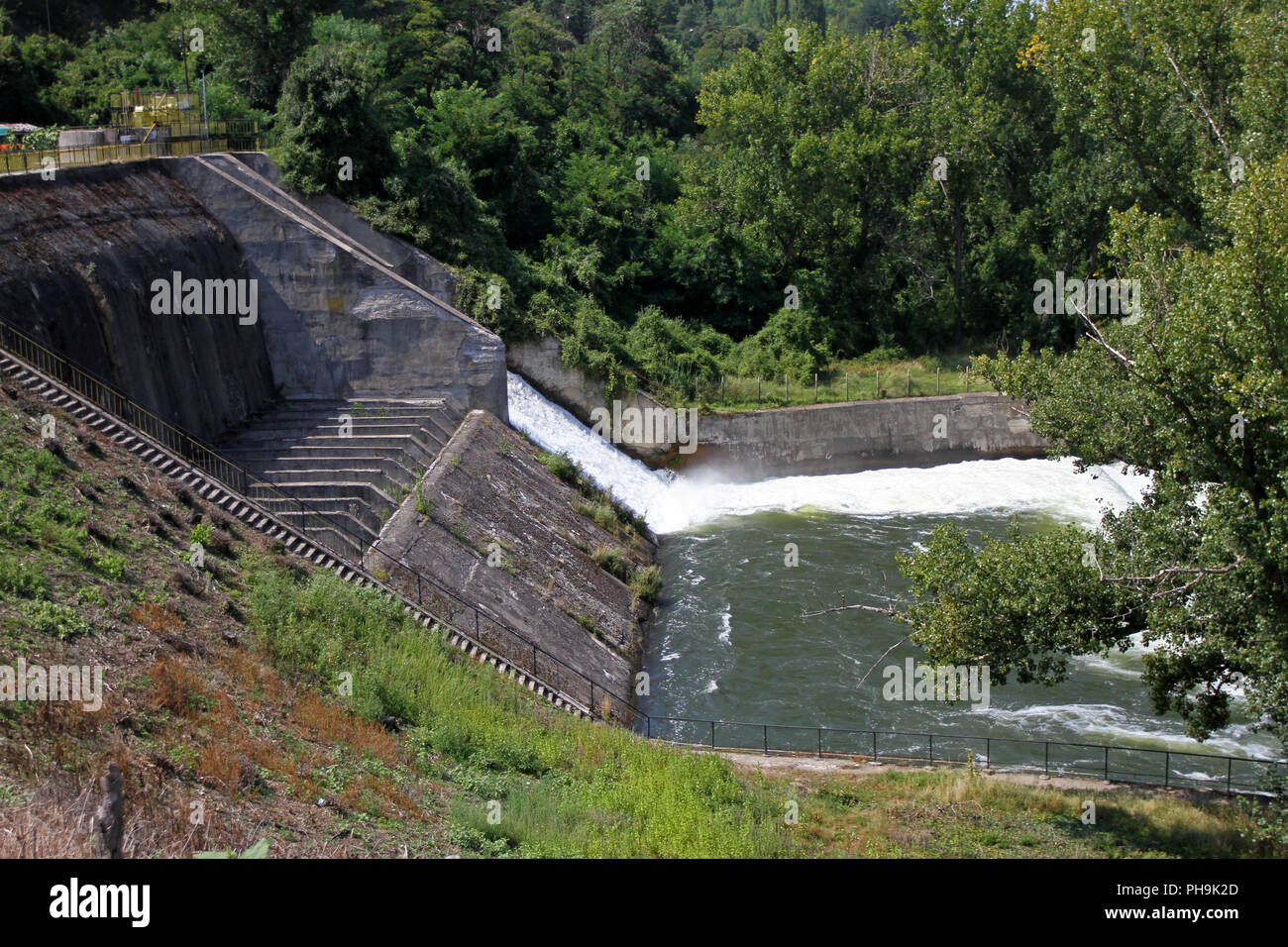 Dam wall and overflow of Iskar Dam. Water flowing over a dam wall. Mist ...
