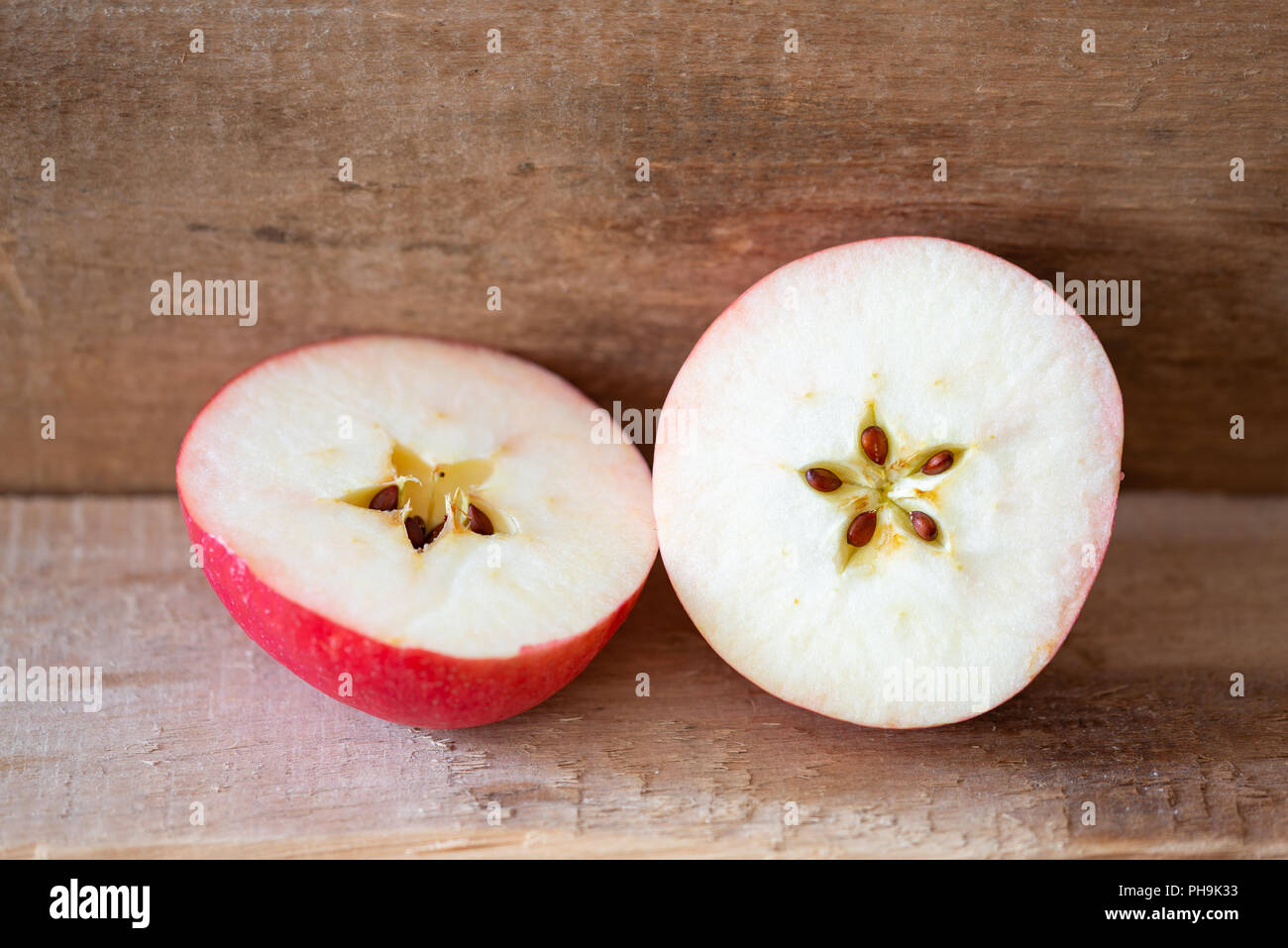 Cut apple on a wooden plank, showing the seeds in a delicate five ...