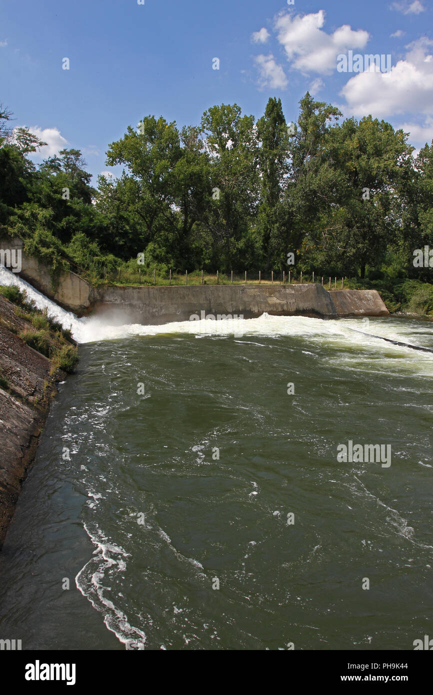 Dam wall and overflow of Iskar Dam. Water flowing over a dam wall. Mist ...