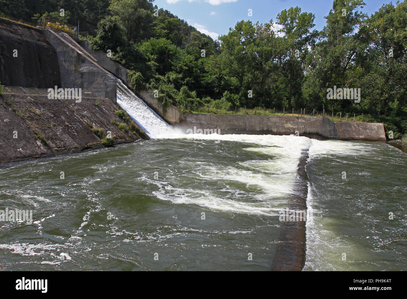 Dam wall and overflow of Iskar Dam. Water flowing over a dam wall. Mist ...