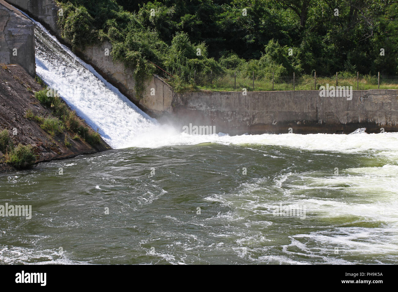 Dam wall and overflow of Iskar Dam. Water flowing over a dam wall. Mist ...