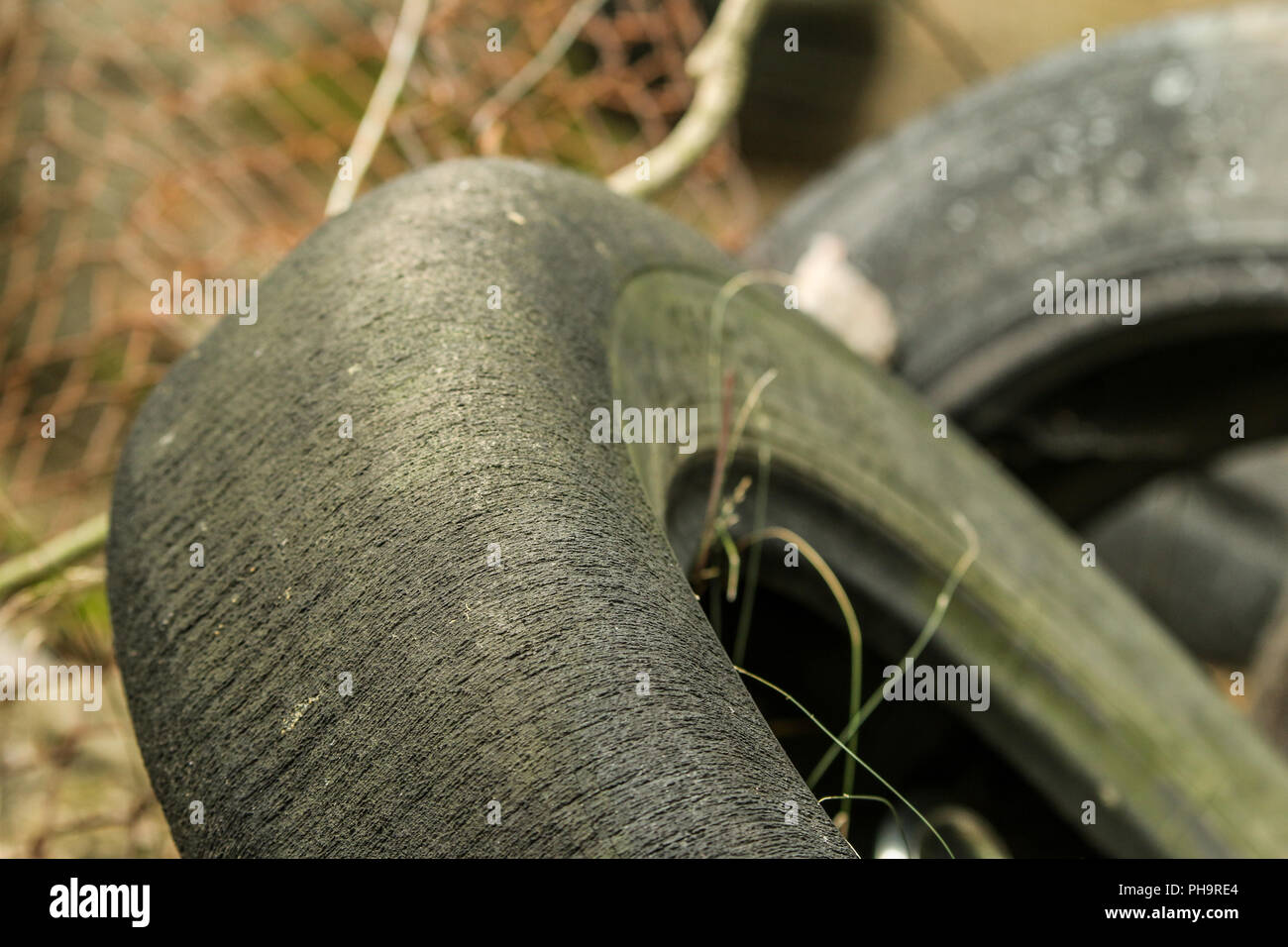 A detail of an old used tire left on a waste dump. The picture of an ...