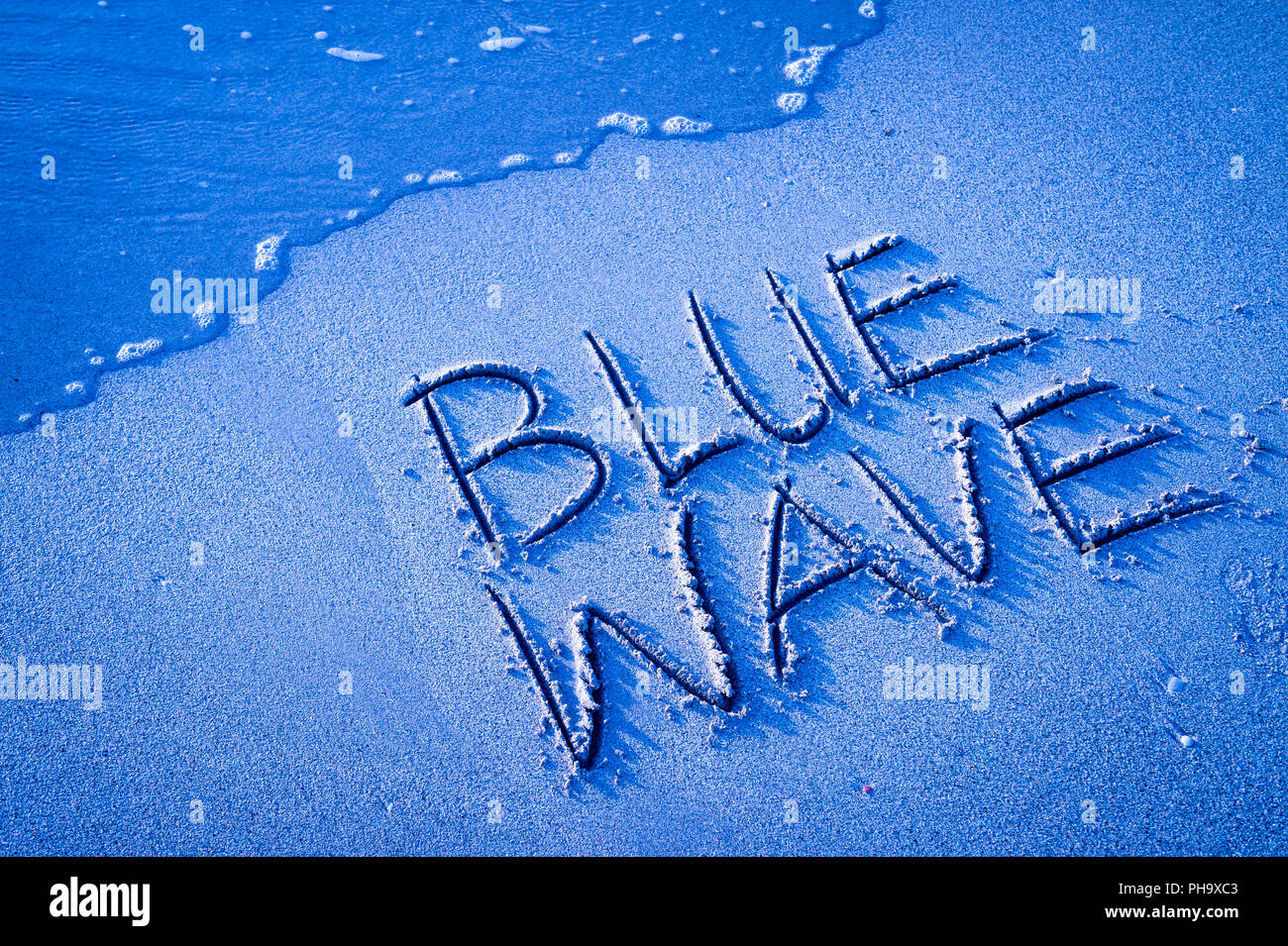 'BLUE WAVE' written in the sand on the beach with the sea washing up ...