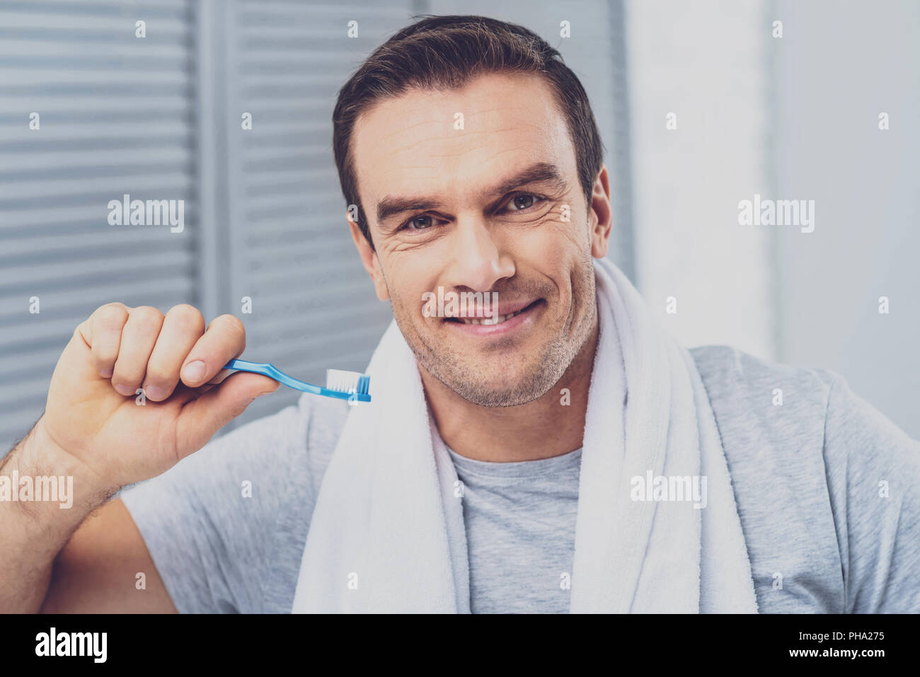 Pleasant man smiling broadly brushing his teeth Stock Photo - Alamy
