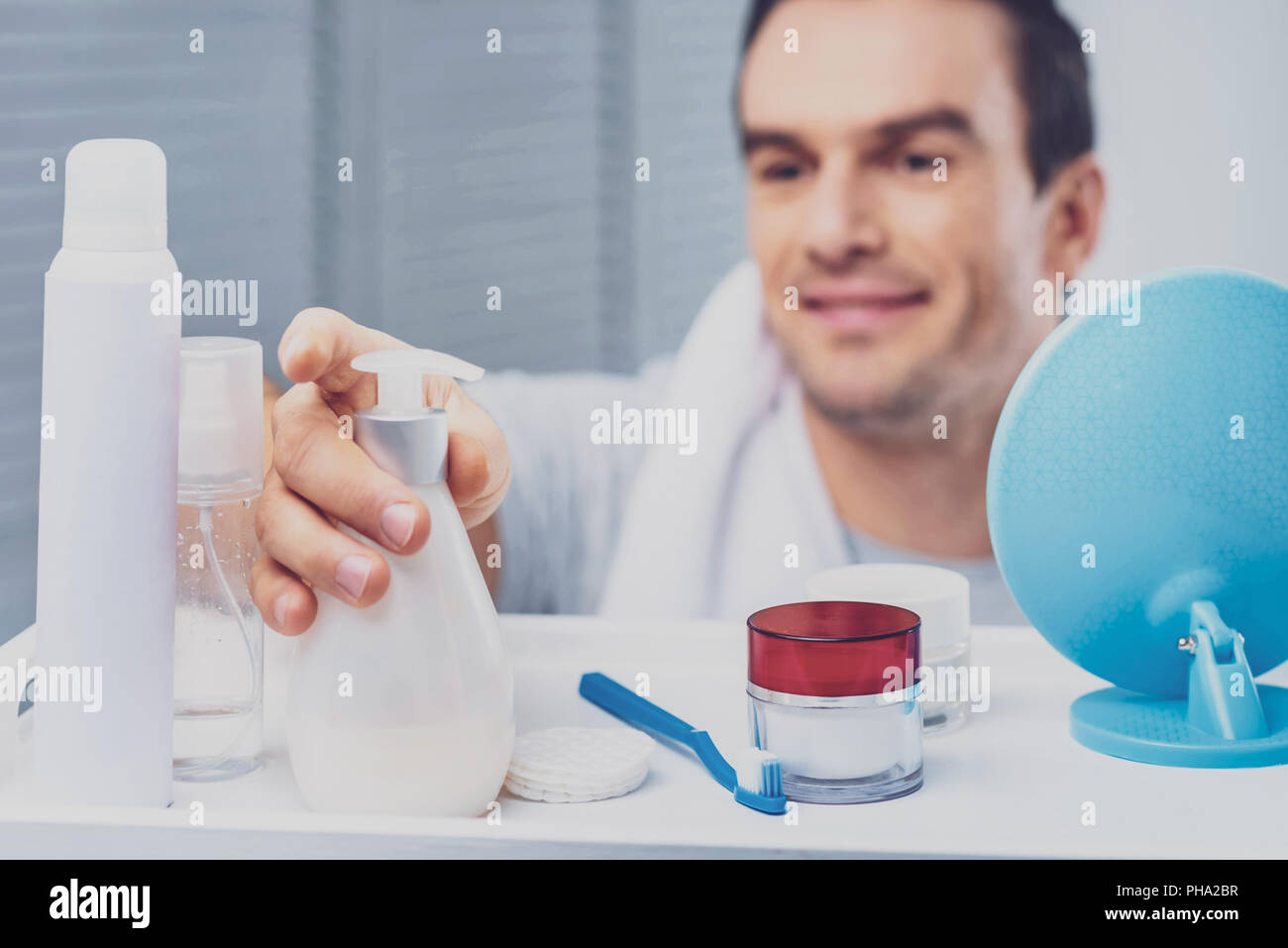 Dark-eyed man putting liquid soap on shelf Stock Photo - Alamy