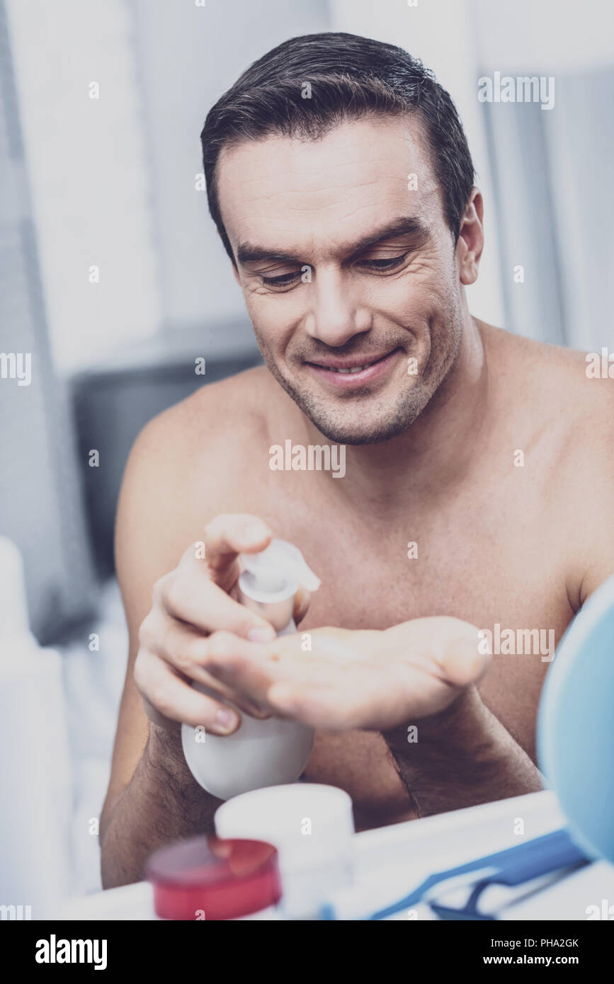 Joyful man holding a bottle of lotion Stock Photo - Alamy