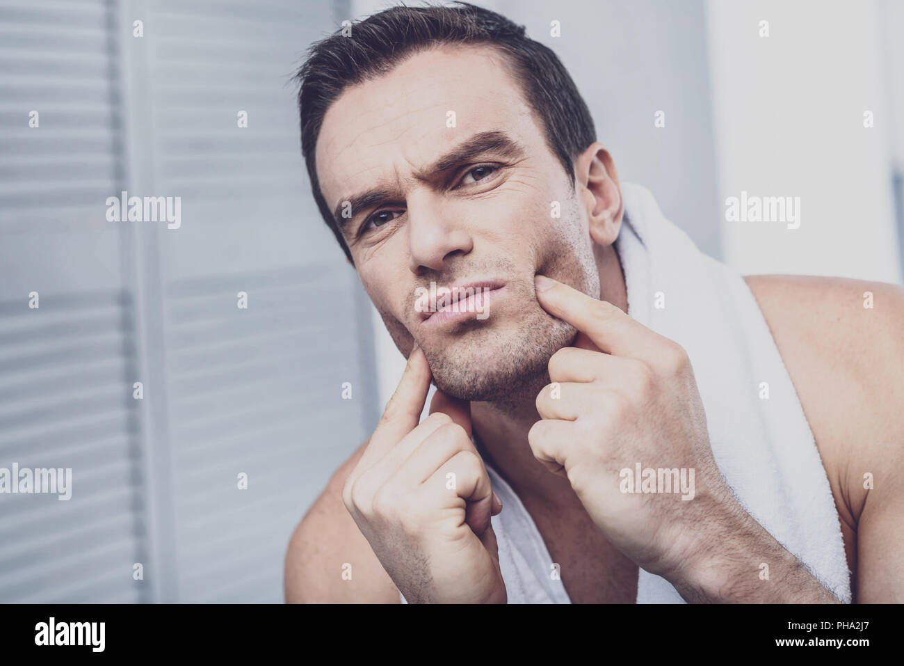 Serious man pressing fingers on his cheeks Stock Photo - Alamy