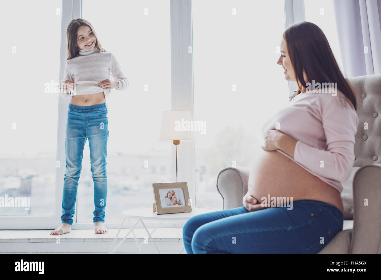 Pregnant mother and her little daughter comparing their stomachs Stock ...