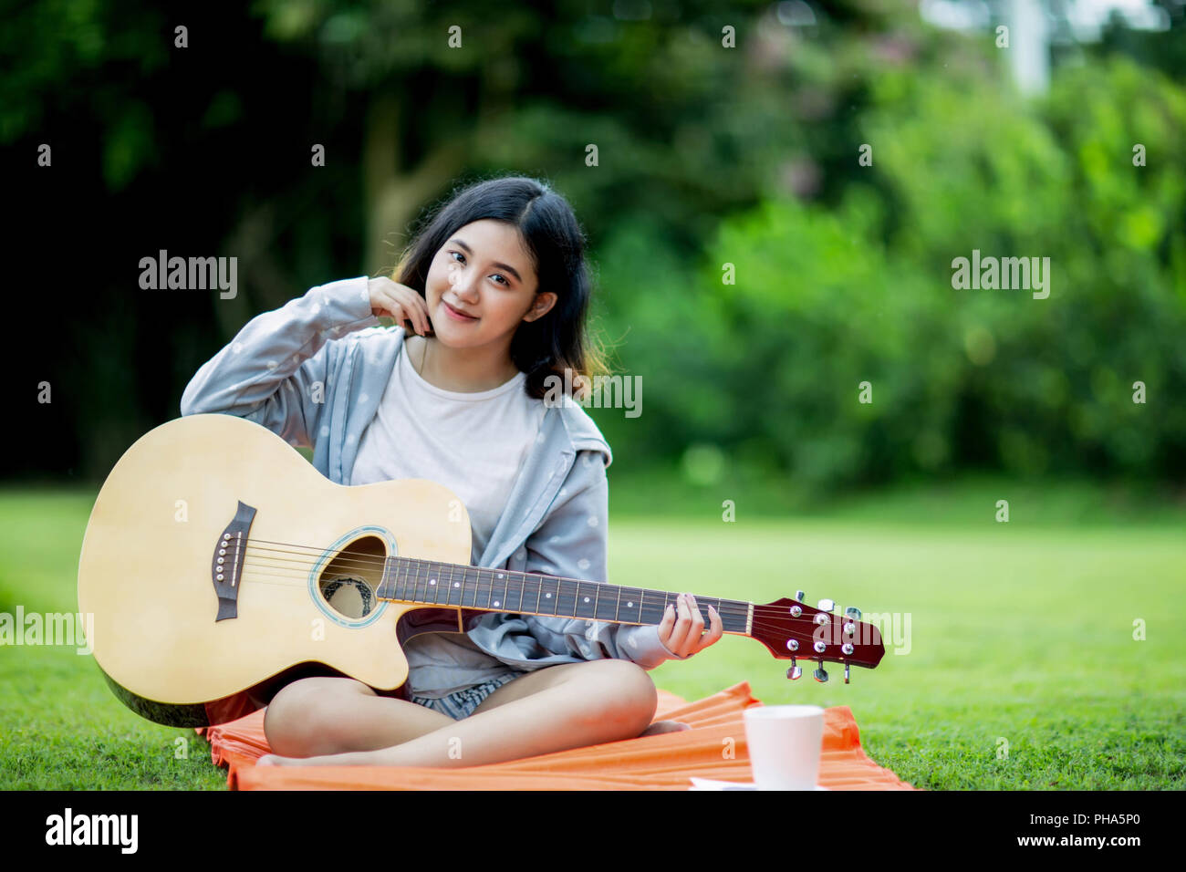 Young asian girl playing guitar in the garden Stock Photo - Alamy