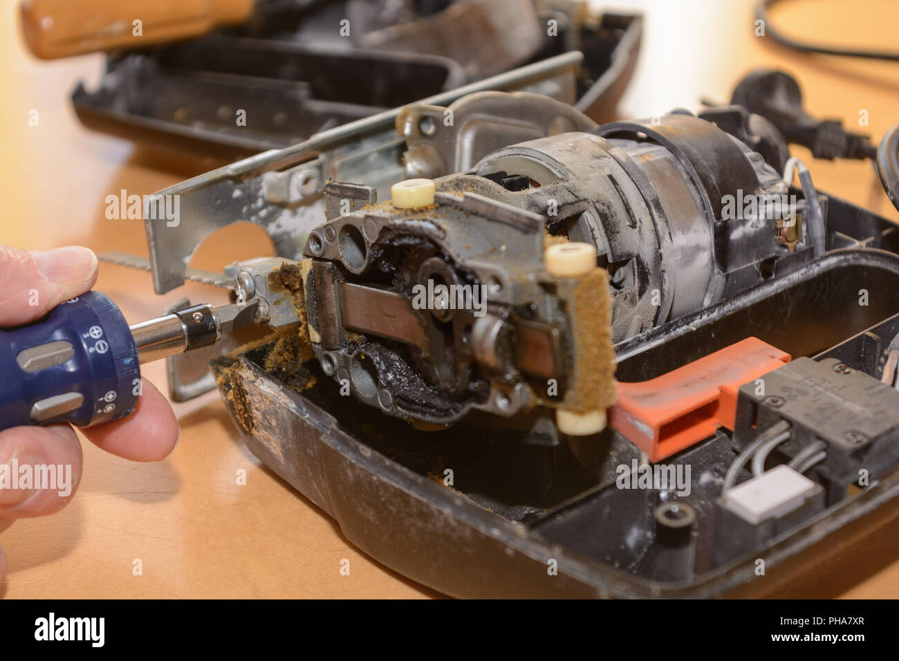 Handyman repairing broken jigsaw with screwdriver - detail Stock Photo ...
