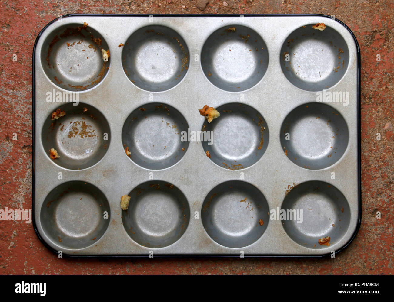 A top view of a dirty metal unwashed baking tray with twelve ...