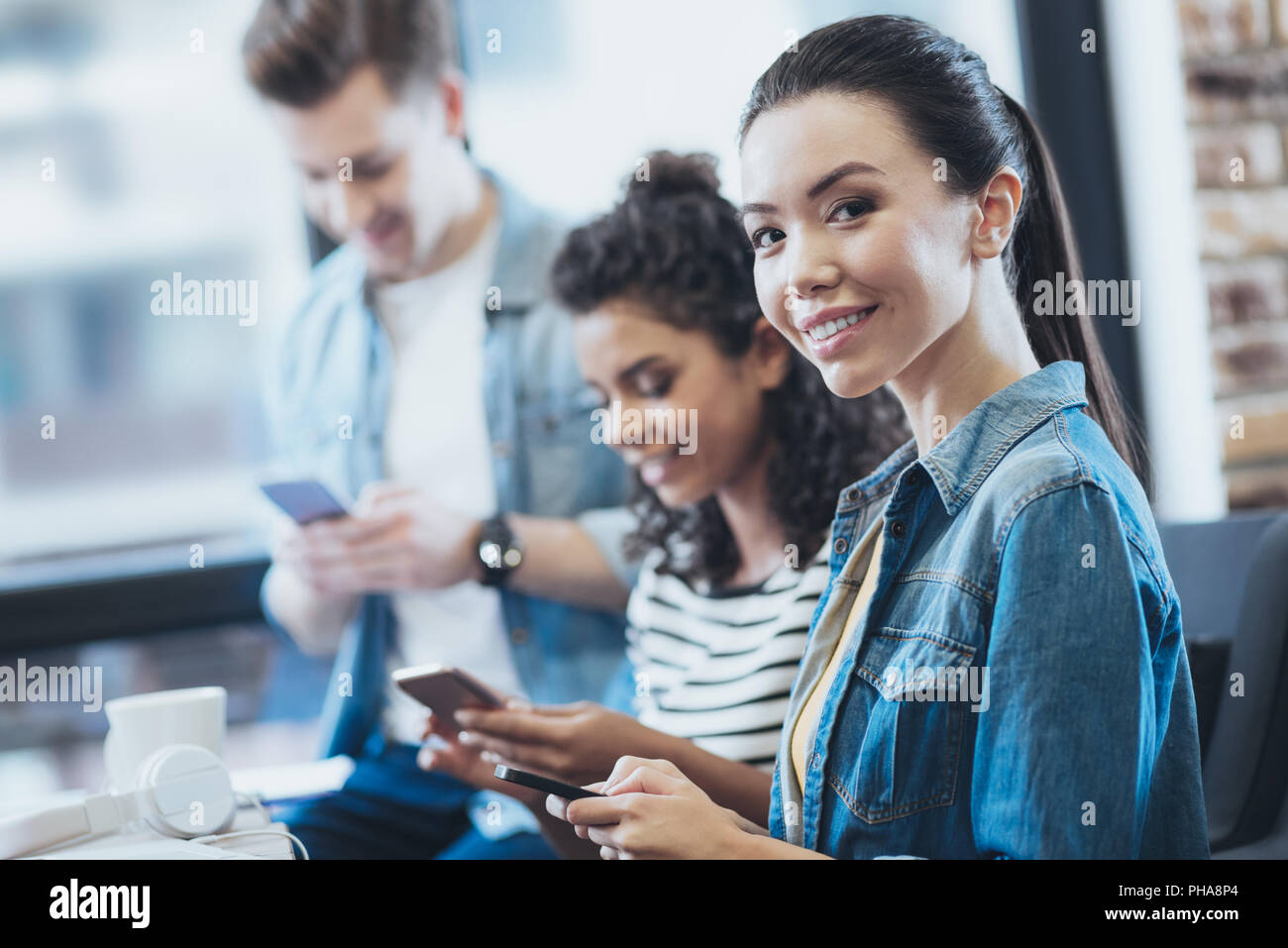Happy three friends using smartphones Stock Photo - Alamy