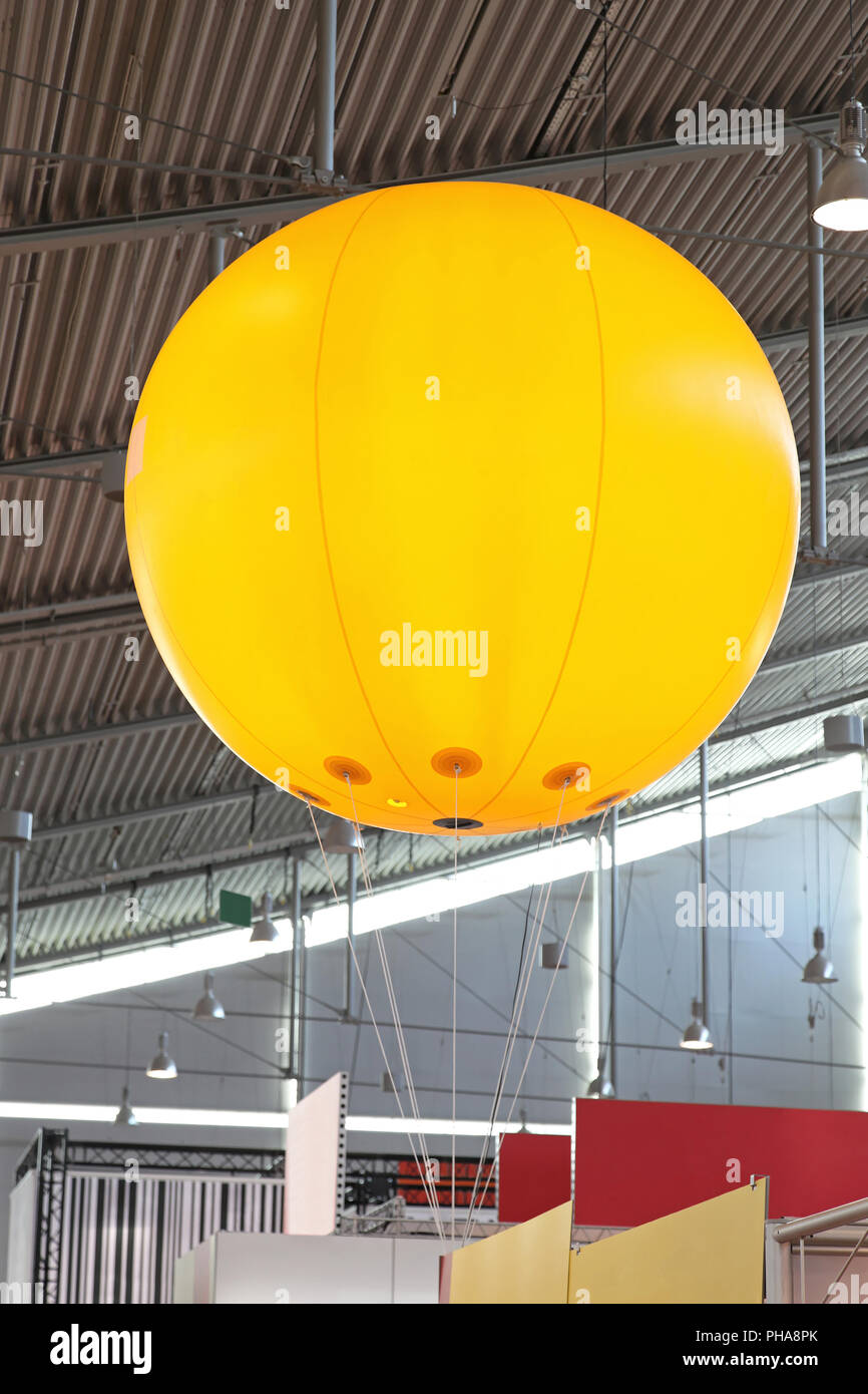 Big yellow advertising balloon in exhibition hall Stock Photo - Alamy