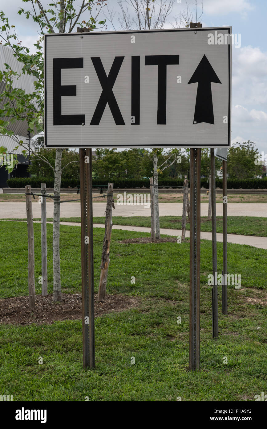 white with black lettering Exit sign outside with green grass below ...