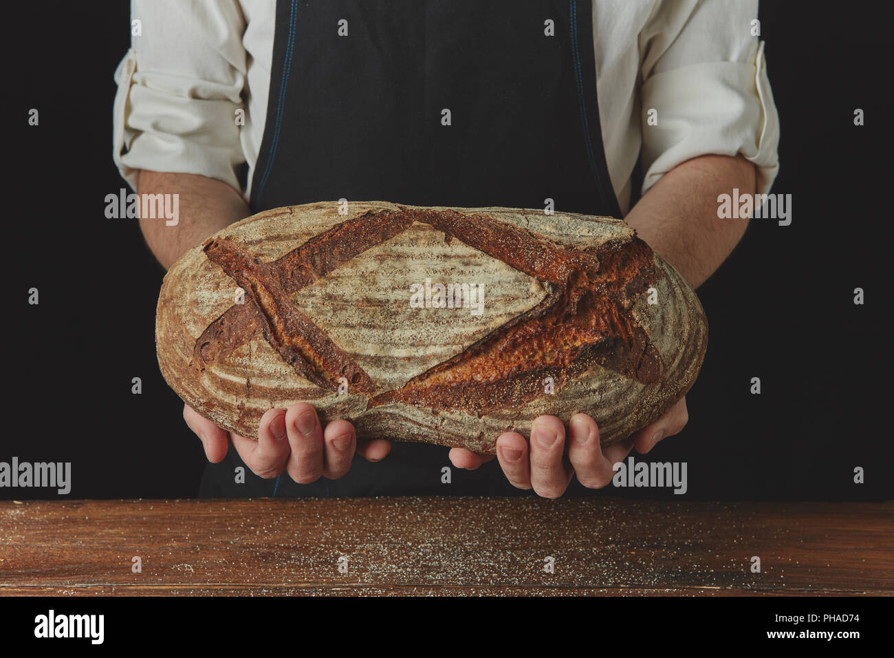 Baker's hands hold an oval bread Stock Photo - Alamy