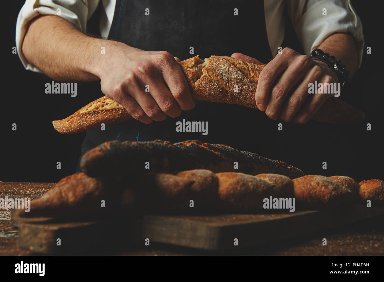 Baker's hands break the baguette Stock Photo - Alamy