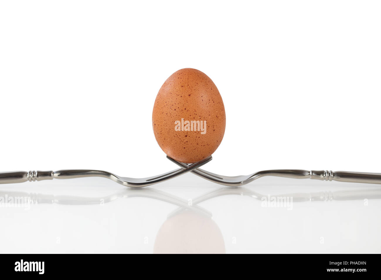 Isolated whole brown egg balanced on two forks Stock Photo - Alamy