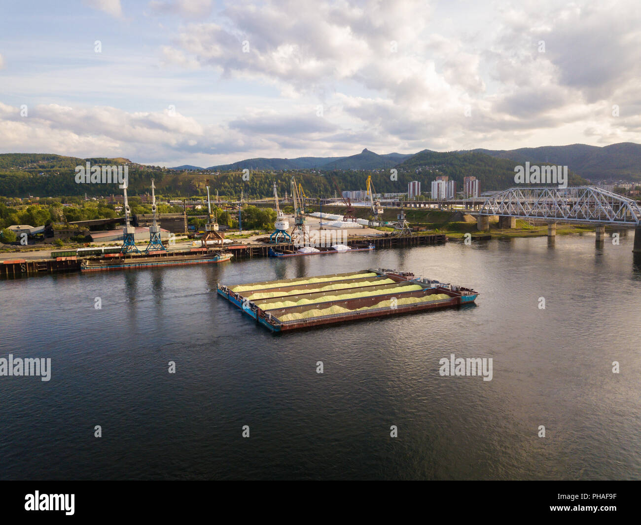 Aerial photo of harbor cranes and and barge with sand over river harbor ...