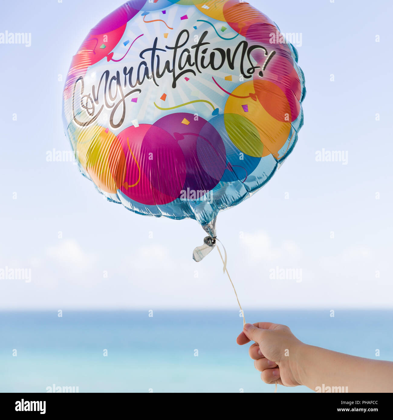 Woman's hand holding colorful baloon on the blue sky background ...